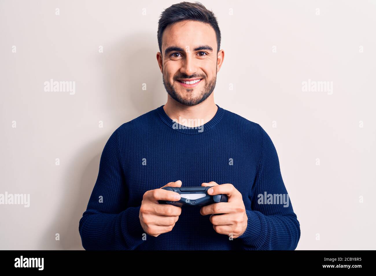 Handsome gamer man with beard playing video game using gamepad over ...