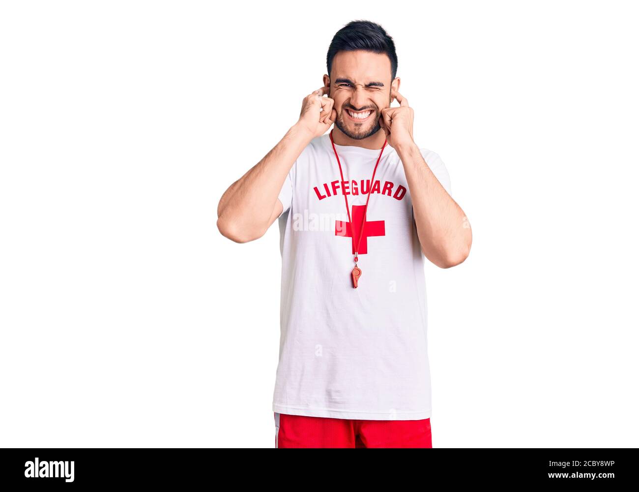 Young handsome man wearing lifeguard uniform covering ears with fingers ...