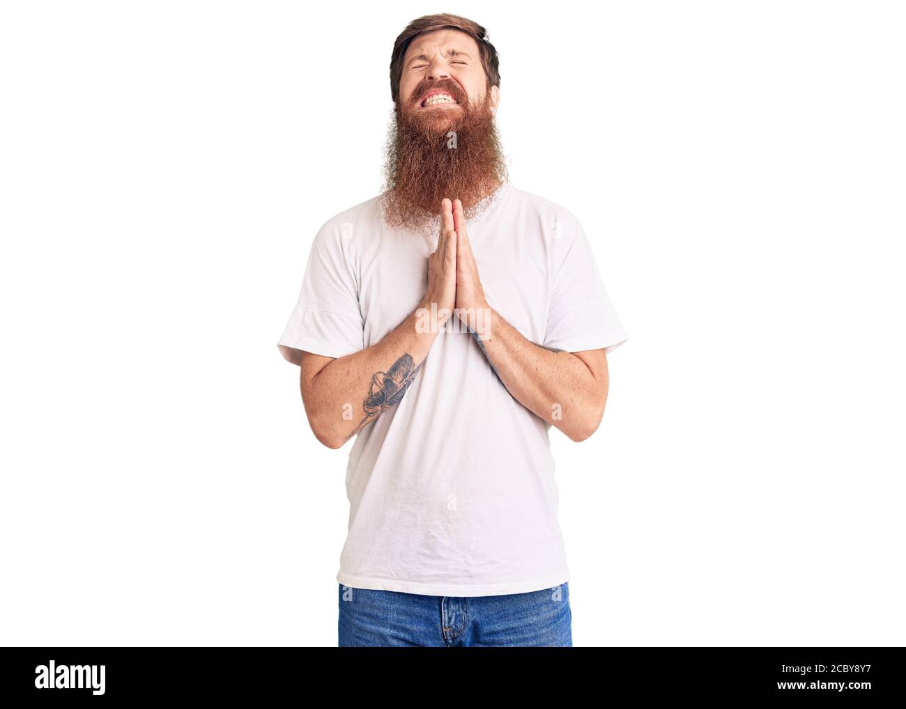 Handsome young red head man with long beard wearing casual white tshirt ...