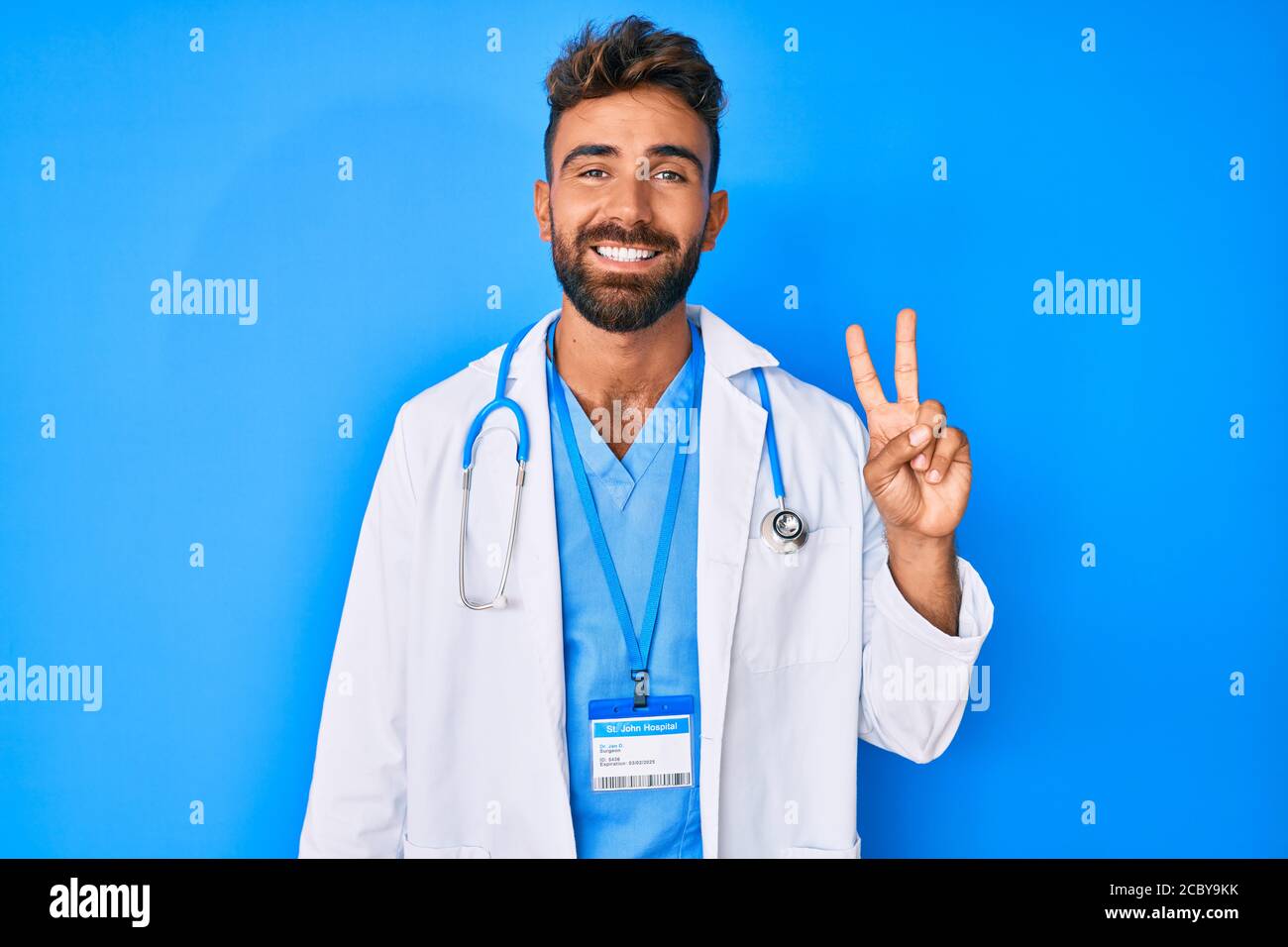 Young hispanic man wearing doctor uniform and stethoscope smiling with ...