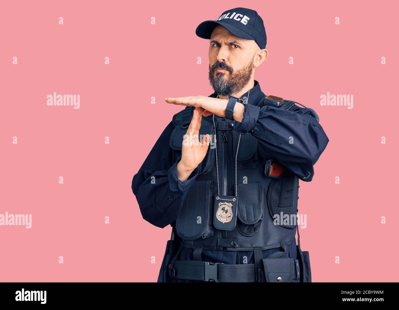 Young handsome man wearing police uniform doing time out gesture with ...
