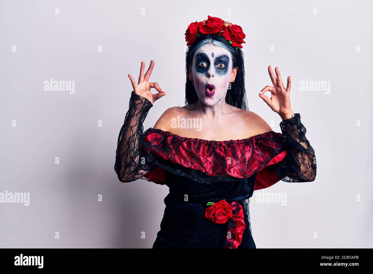 Young woman wearing mexican day of the dead makeup looking surprised ...