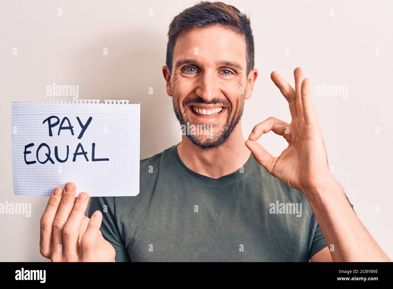 Young handsome man asking for equality economy holding paper with pay ...