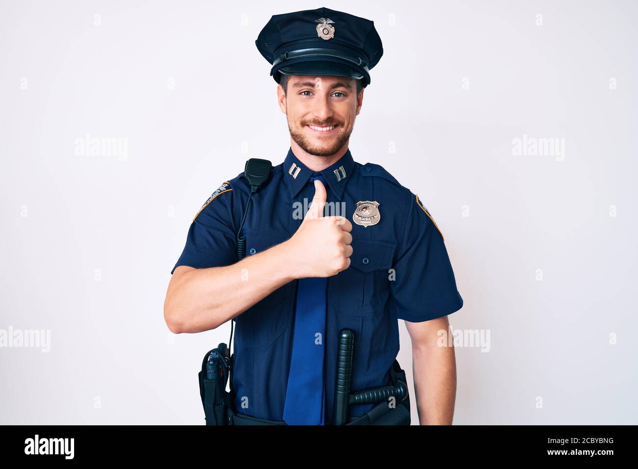 Young caucasian man wearing police uniform doing happy thumbs up ...