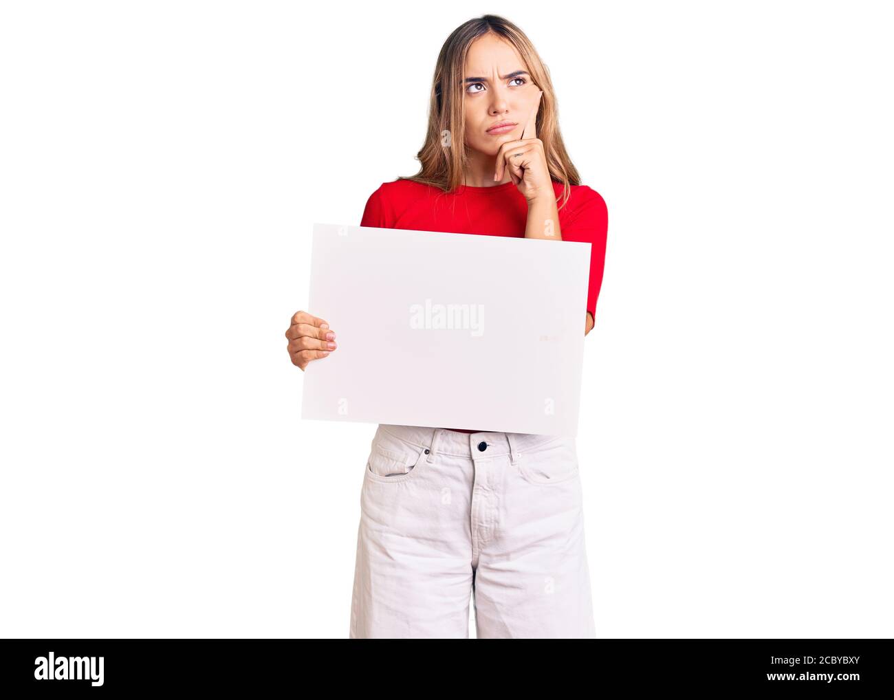 Young beautiful blonde woman holding blank empty banner serious face ...