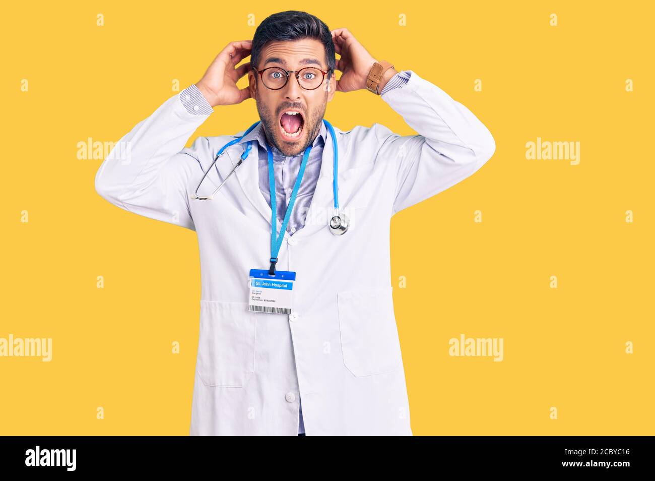 Young hispanic man wearing doctor uniform and stethoscope crazy and ...