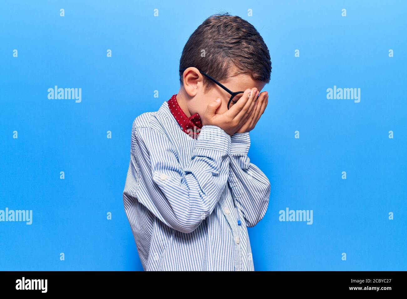 Cute blond kid wearing nerd bow tie and glasses with sad expression ...