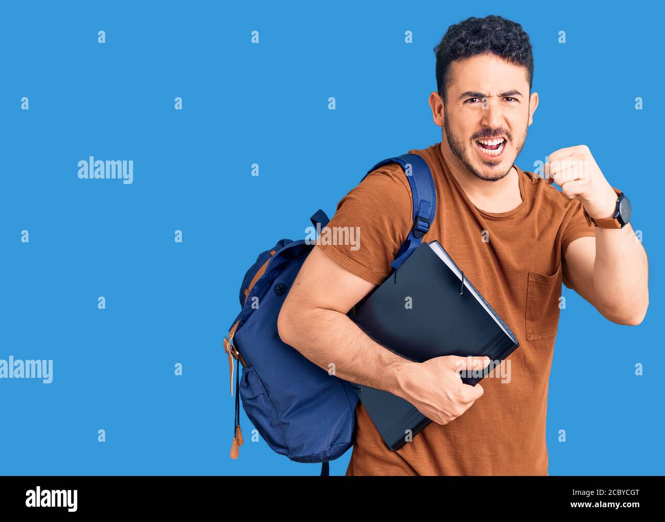 Young hispanic man wearing student backpack holding binder annoyed and ...