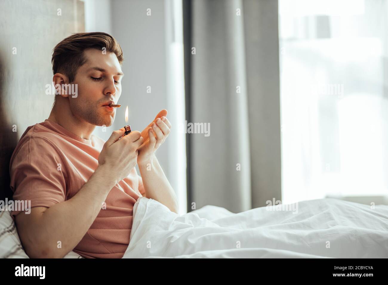 handsome caucasian man smoking cannabis weed at home in bedroom. he use ...