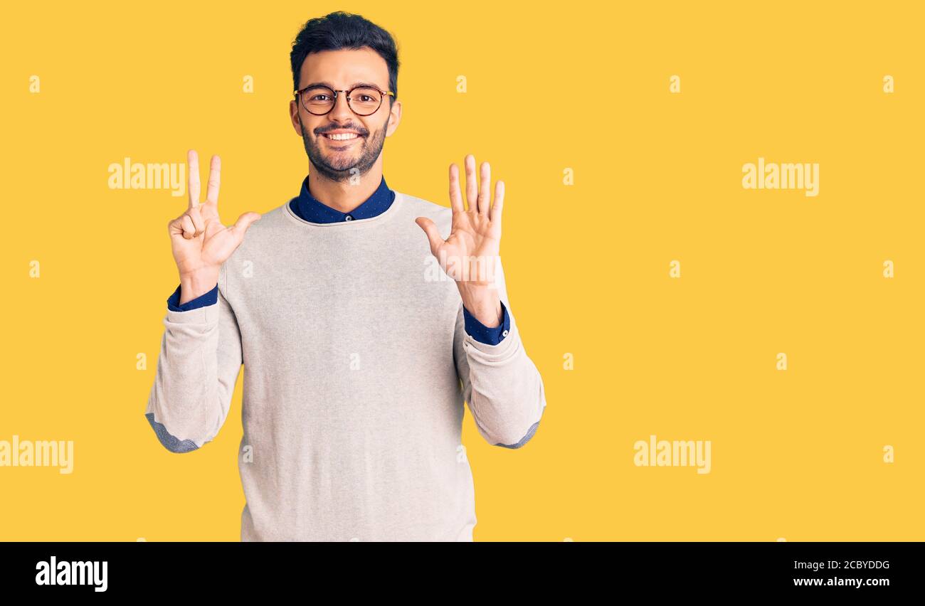 Young handsome hispanic man wearing elegant clothes and glasses showing ...