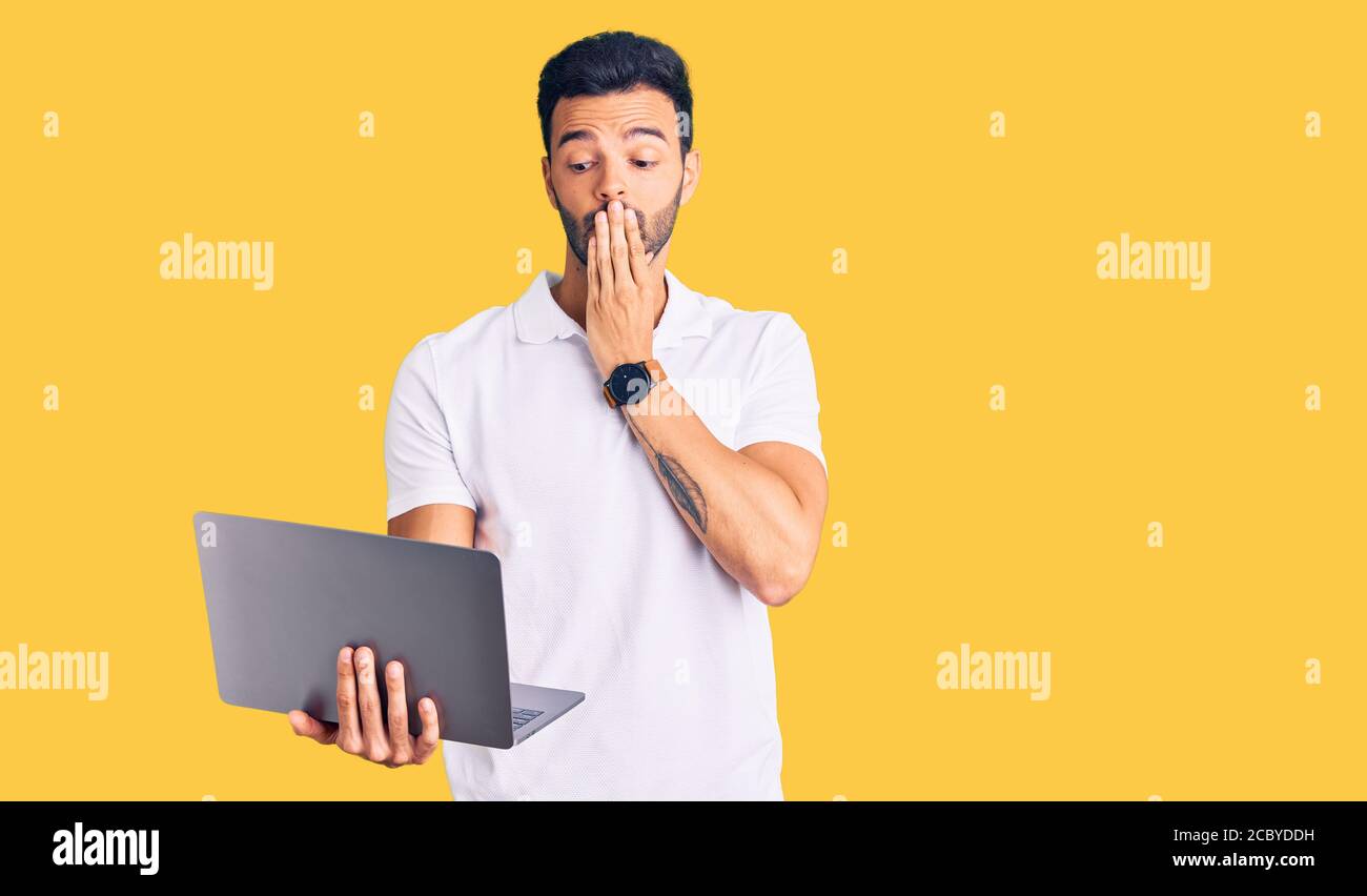 Young handsome hispanic man working using computer laptop covering ...