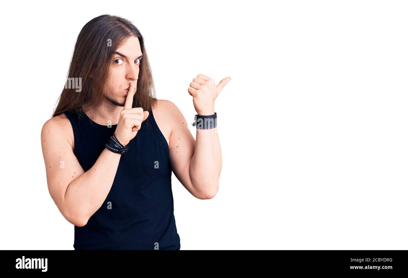Young adult man with long hair wearing goth style with black clothes ...