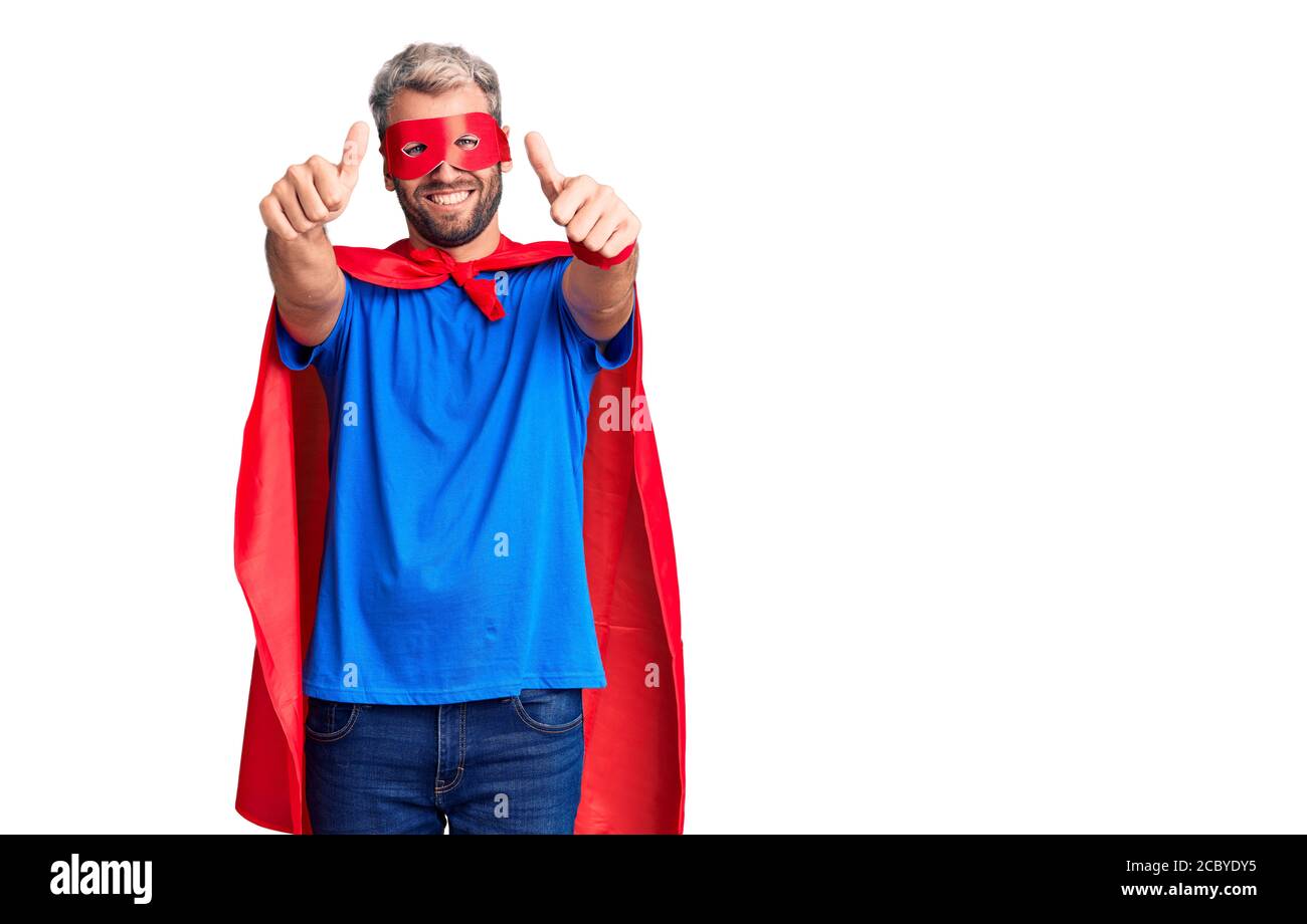 Young blond man wearing super hero custome approving doing positive ...