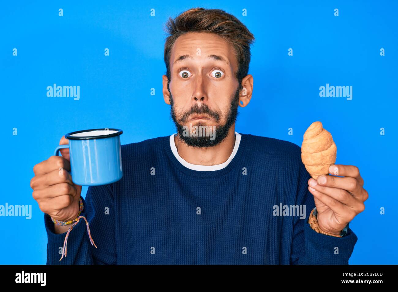 Handsome caucasian man with beard drinking a cup of coffee and ...
