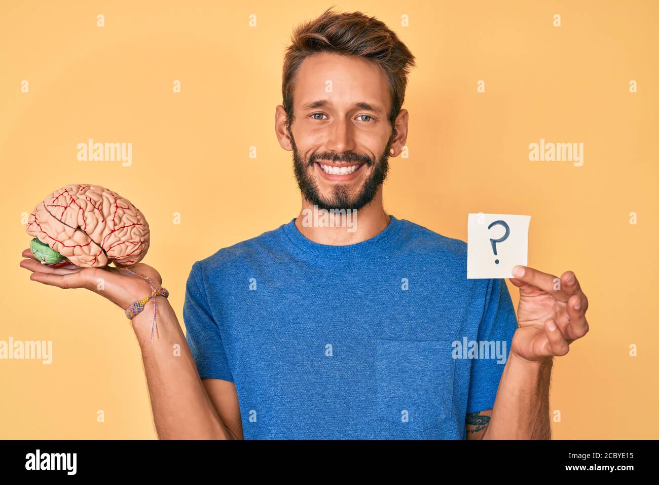 Handsome caucasian man with beard holding brain and question mark ...