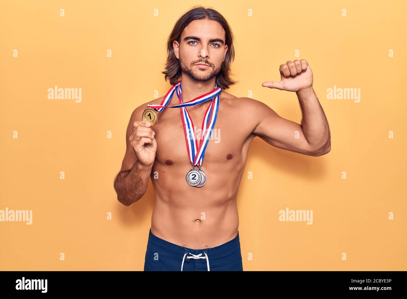 Young handsome man wearing swimwear and medals with angry face ...