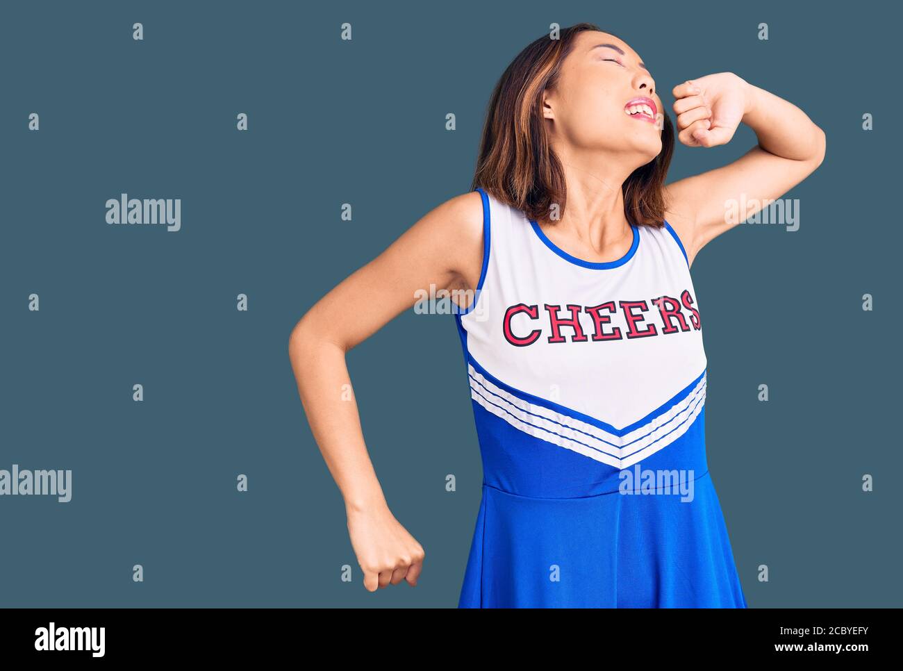 Young beautiful chinese girl wearing cheerleader uniform stretching ...