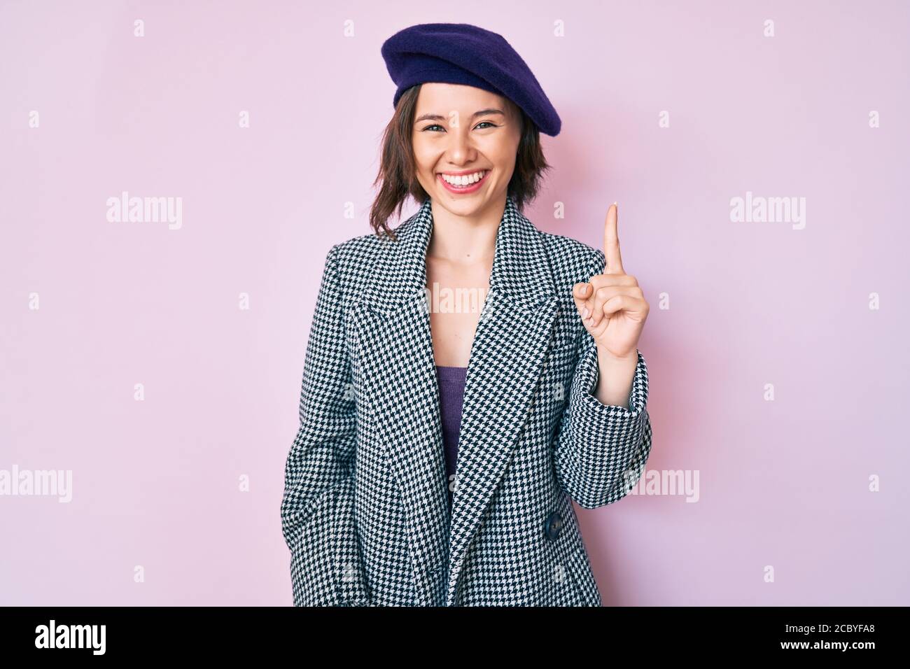 Young beautiful woman wearing french look with beret pointing finger up ...