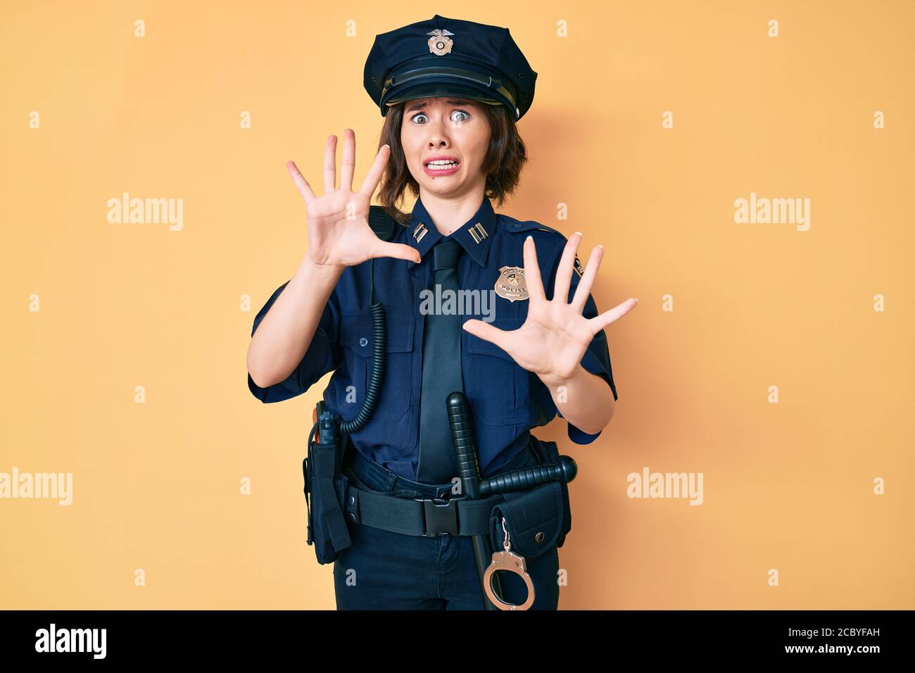Young beautiful woman wearing police uniform afraid and terrified with ...