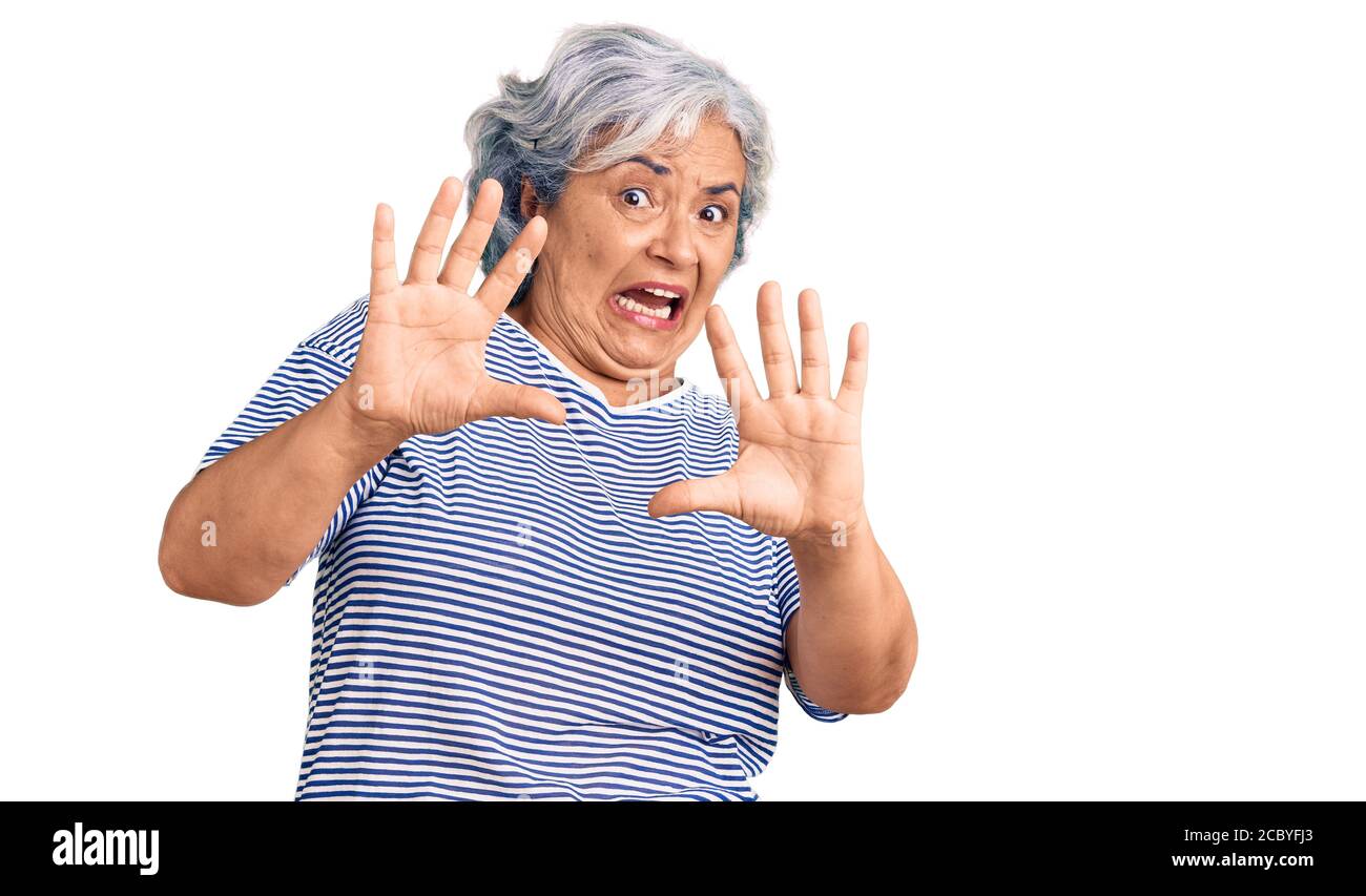 Senior woman with gray hair wearing casual striped clothes afraid and ...