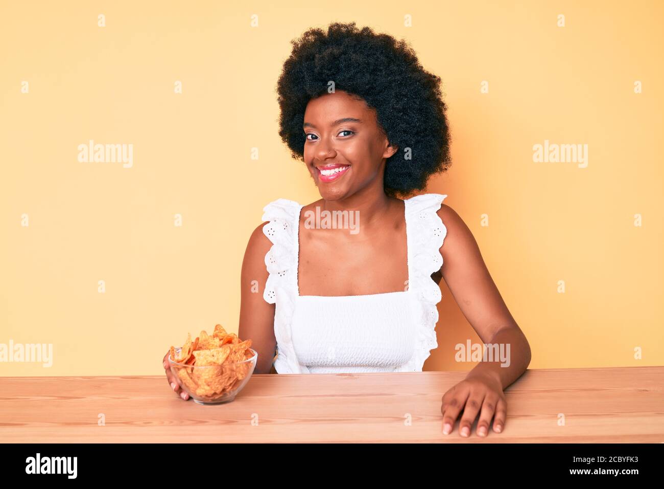 Young african american woman holding nachos potato chips looking ...