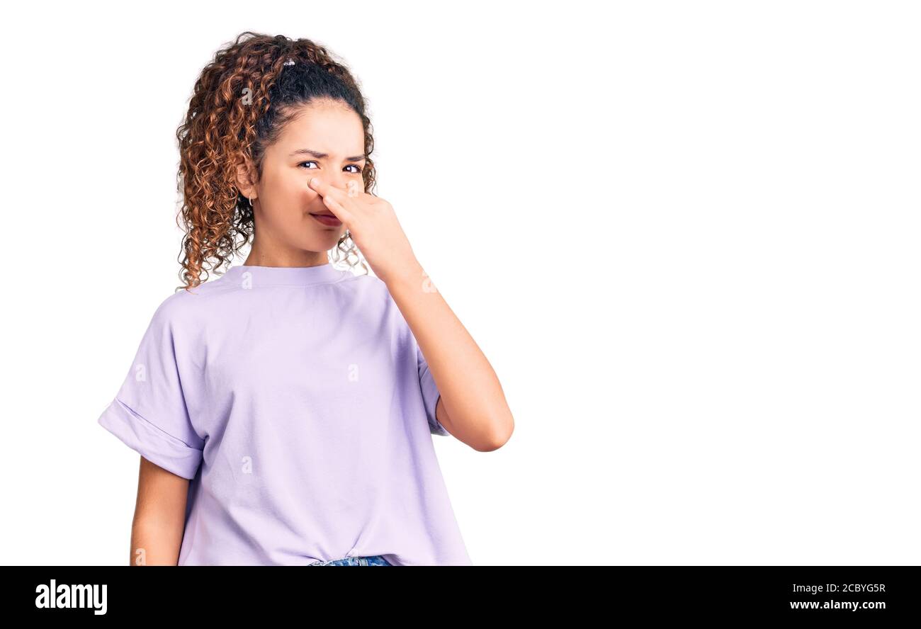 Beautiful kid girl with curly hair wearing casual clothes smelling ...