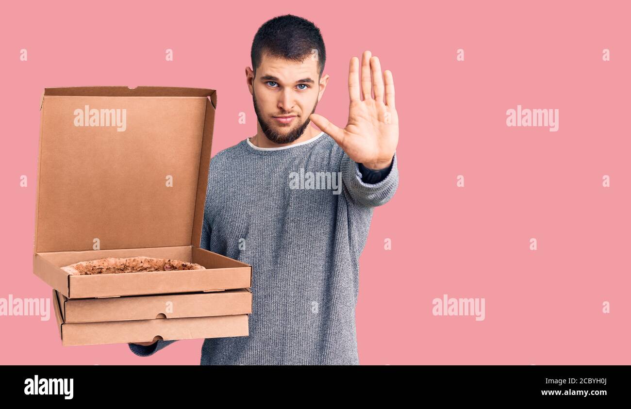 Young handsome man holding delivery italian pizza boxes with open hand ...