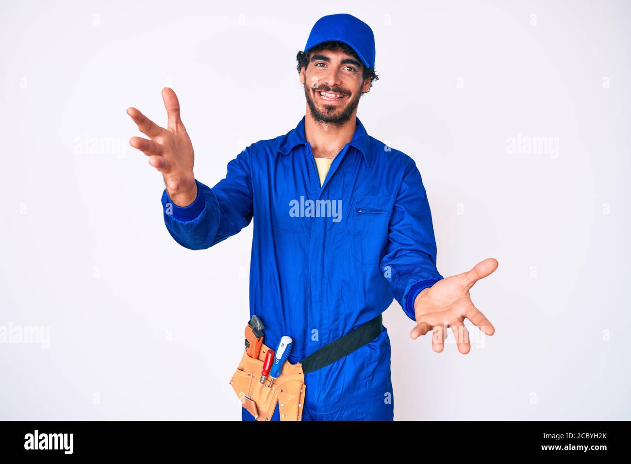 Handsome young man with curly hair and bear weaing handyman uniform ...