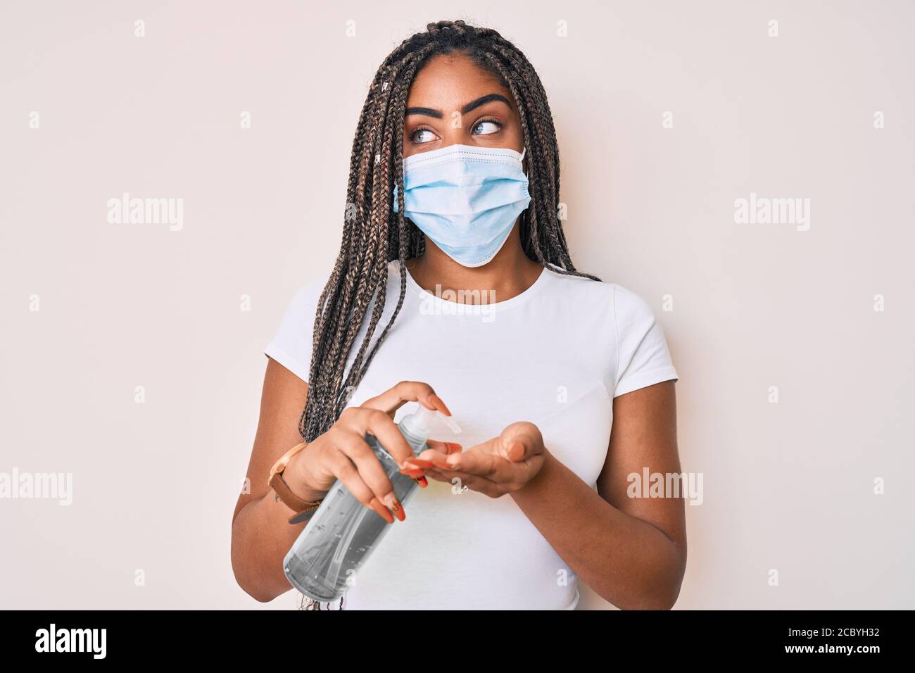 Young african american woman with braids wearing medical mask using ...