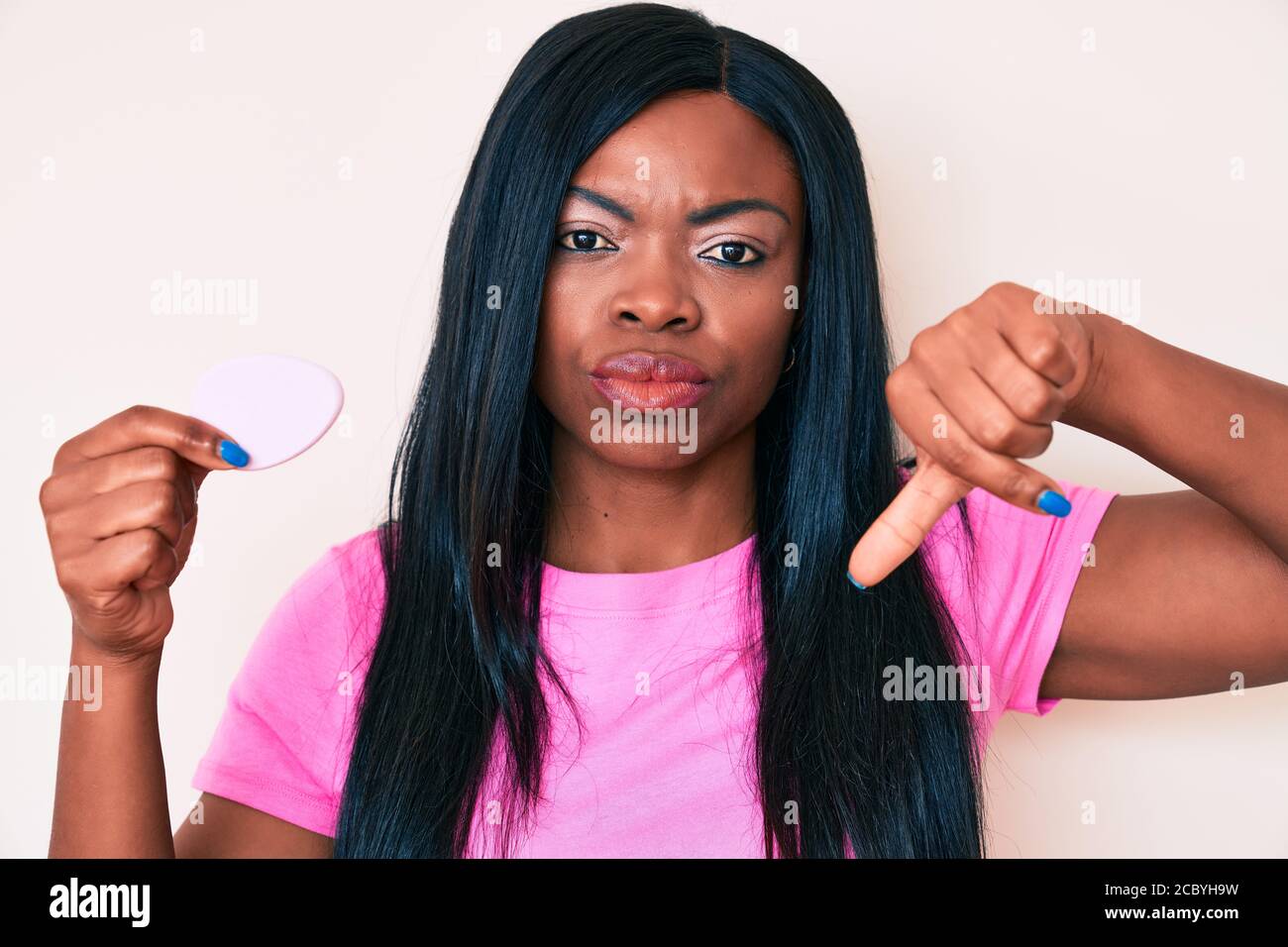 Young african american woman holding makeup sponge with angry face ...