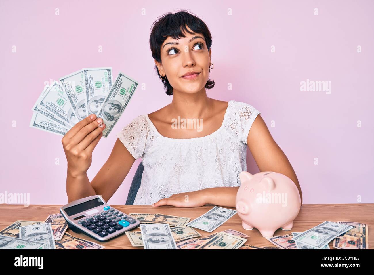 Beautiful brunettte woman holding dollars calculating savings smiling ...