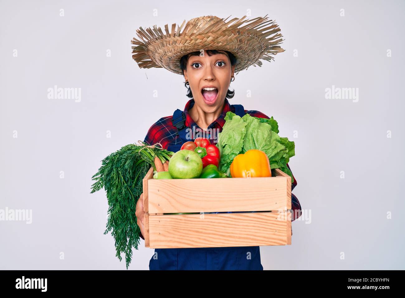 Beautiful brunettte woman wearing farmer clothes holding vegetables ...
