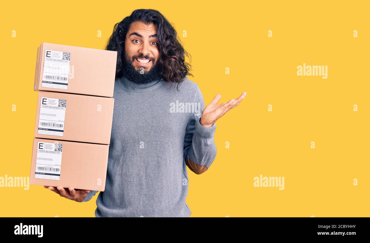 Young arab man holding delivery package celebrating victory with happy ...