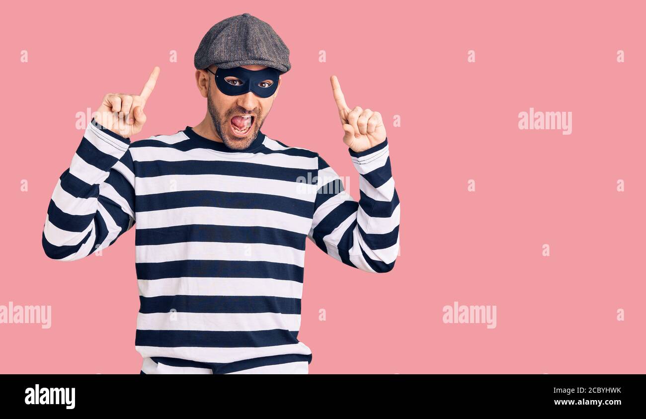 Young handsome man wearing burglar mask smiling amazed and surprised ...