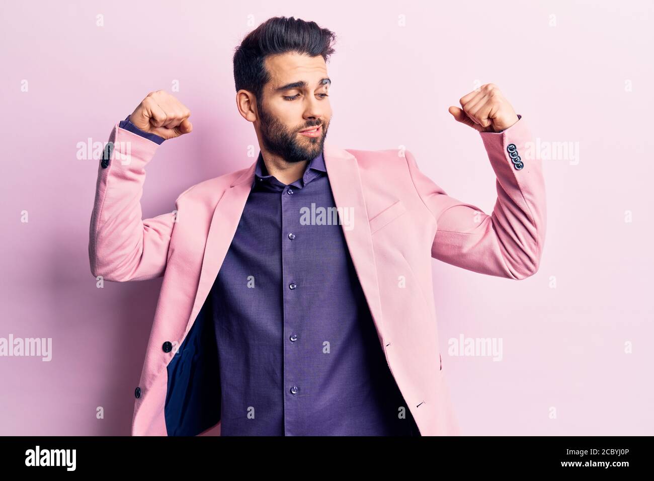 Young handsome man with beard wearing elegant jacket showing arms ...