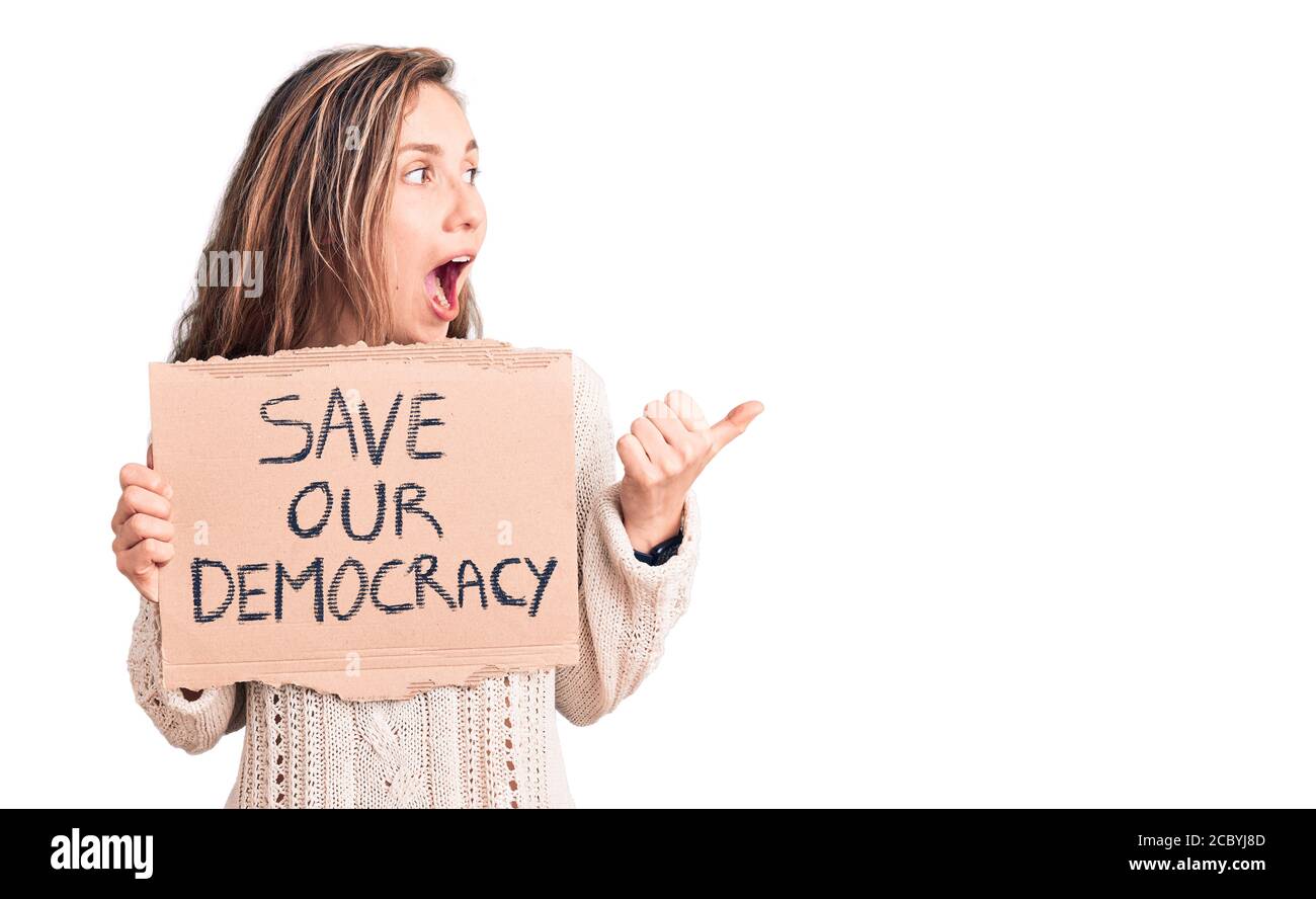 Young beautiful blonde woman holding save our democracy banner pointing ...