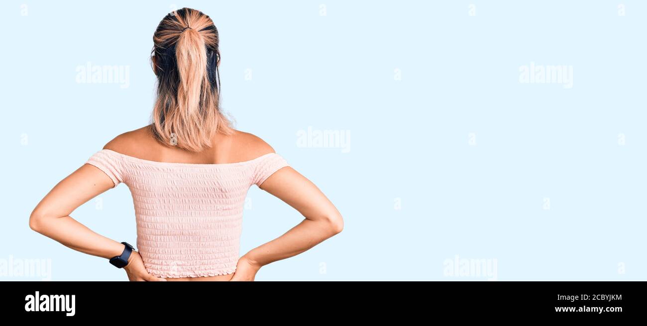 Young beautiful woman wearing casual clothes standing backwards looking ...