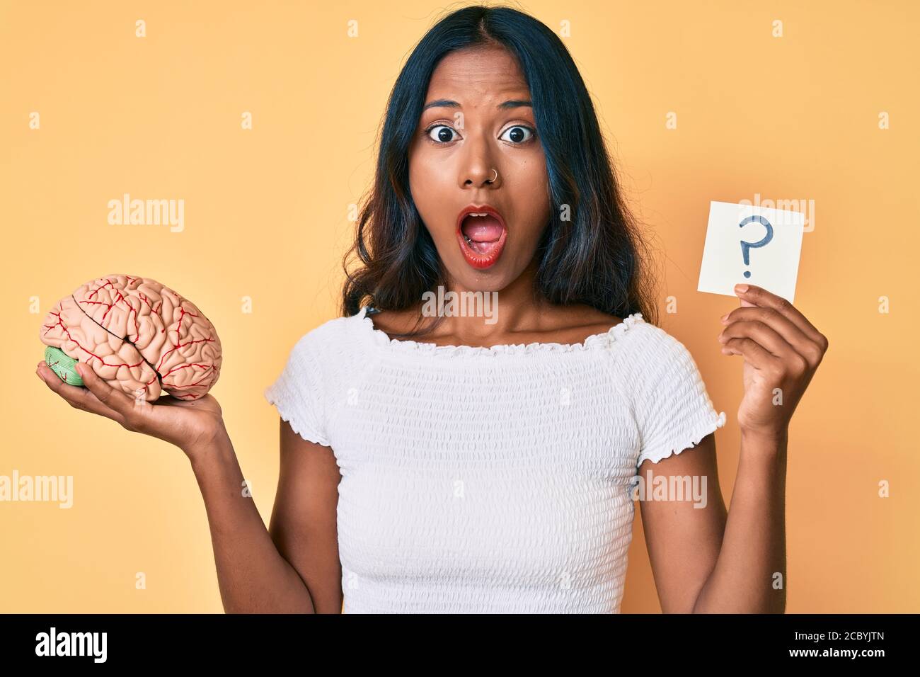 Young indian girl holding brain and question mark reminder afraid and ...