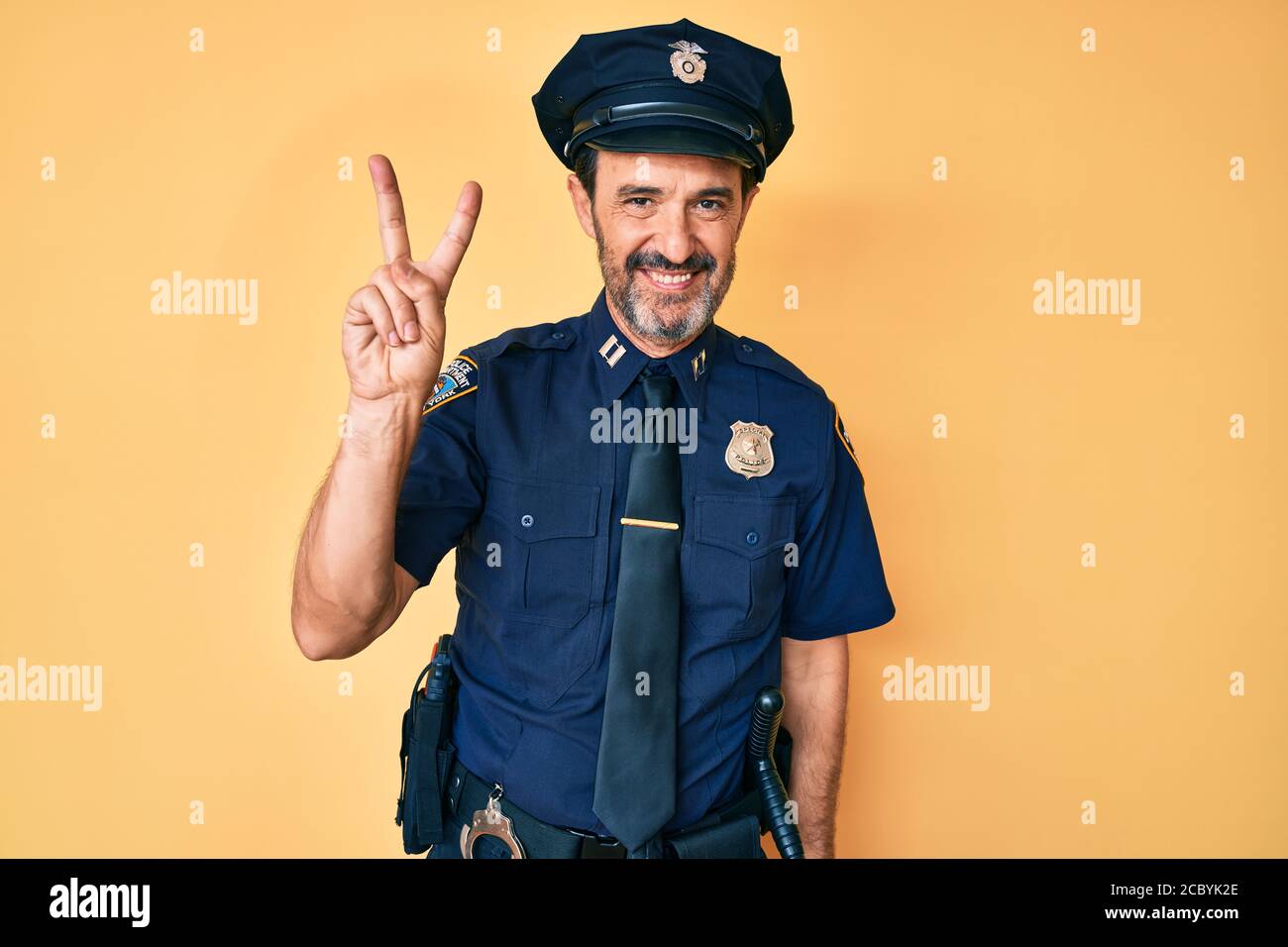 Middle age hispanic man wearing police uniform smiling looking to the ...