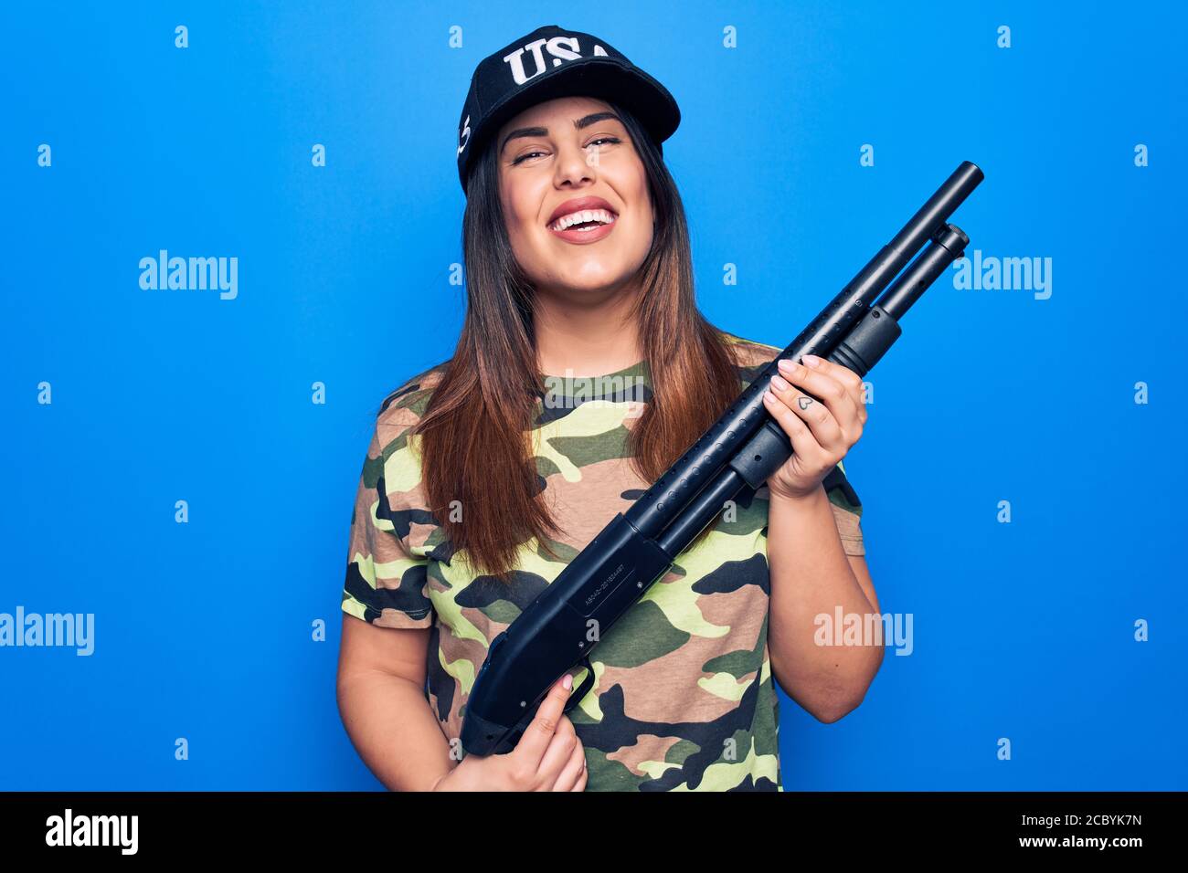 Young beautiful hunter woman wearing camouflage t-shirt and usa cap ...