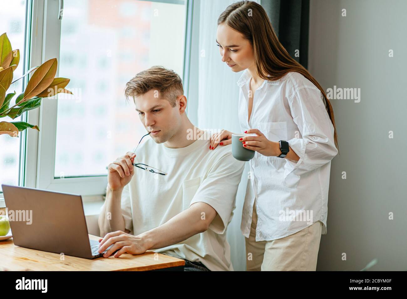 careful caucasian wife support her husband while he is working from ...