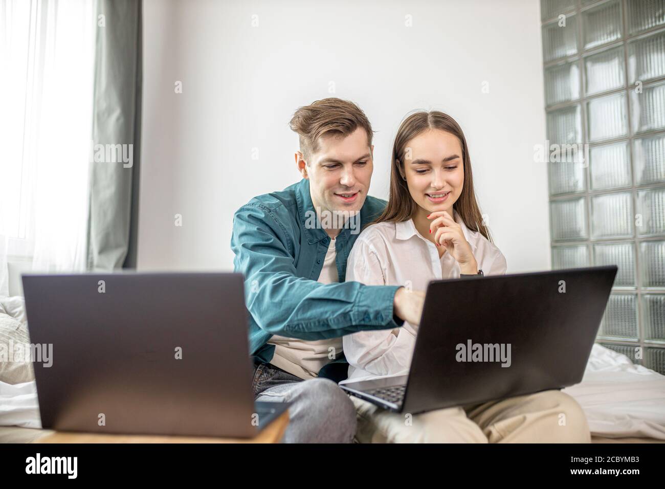 young married couple use their personal laptop. woman sit watching ...