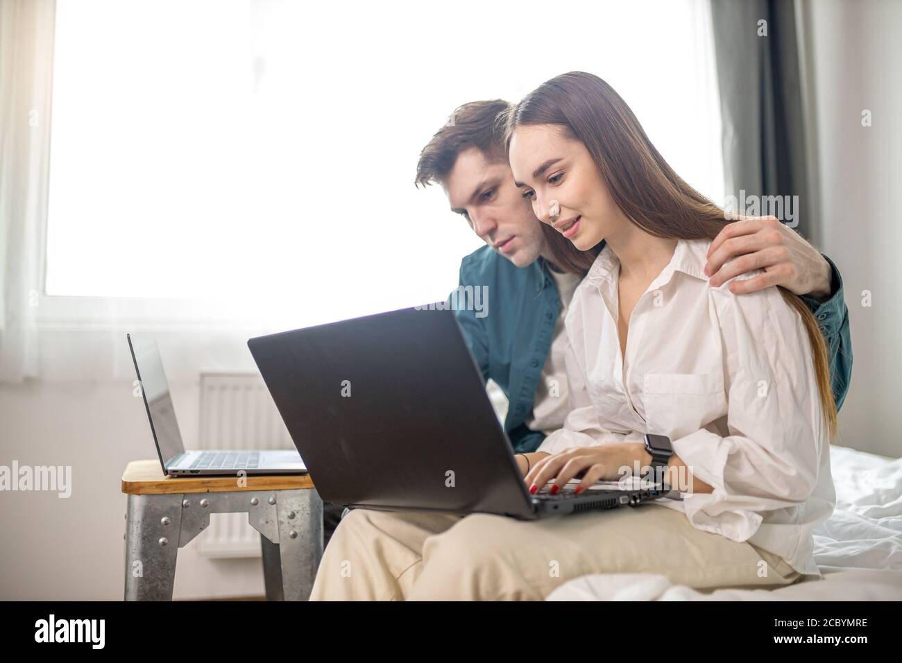 young caucasian married couple work together at home using laptop, man ...