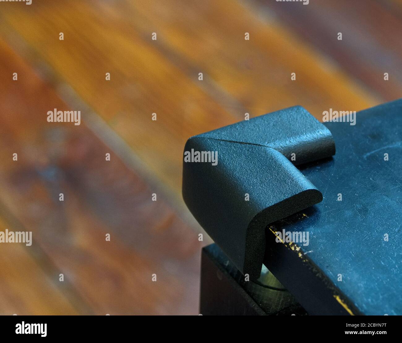 A black child protective corner pad on the corner of a black table ...