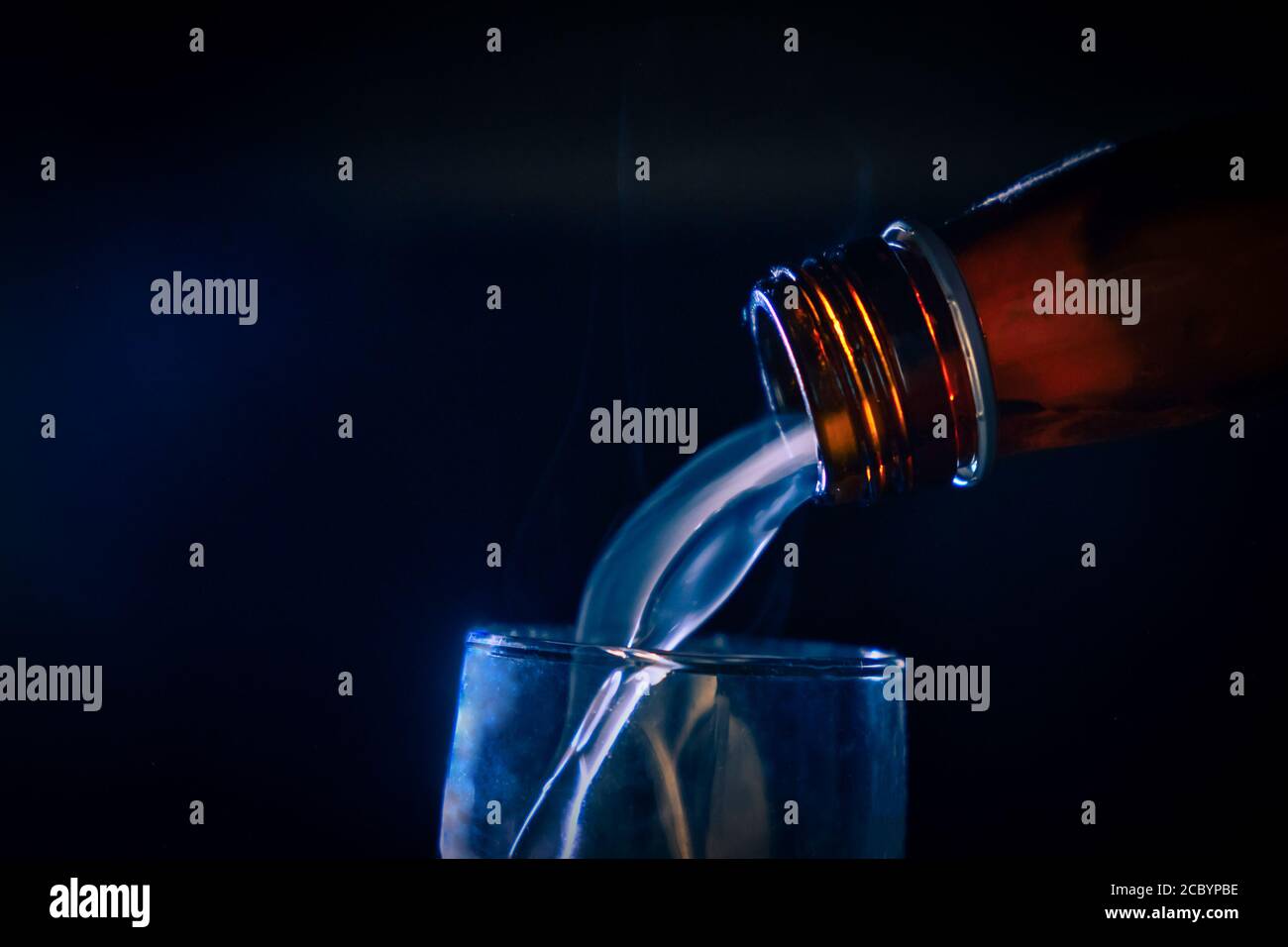 In the dark room of the bottle neck together with the liquor pours a ...