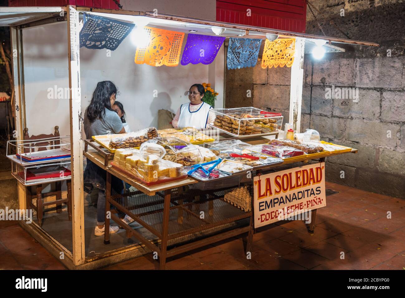 A food stand selling baked snacks at night on a plaza in the historic ...