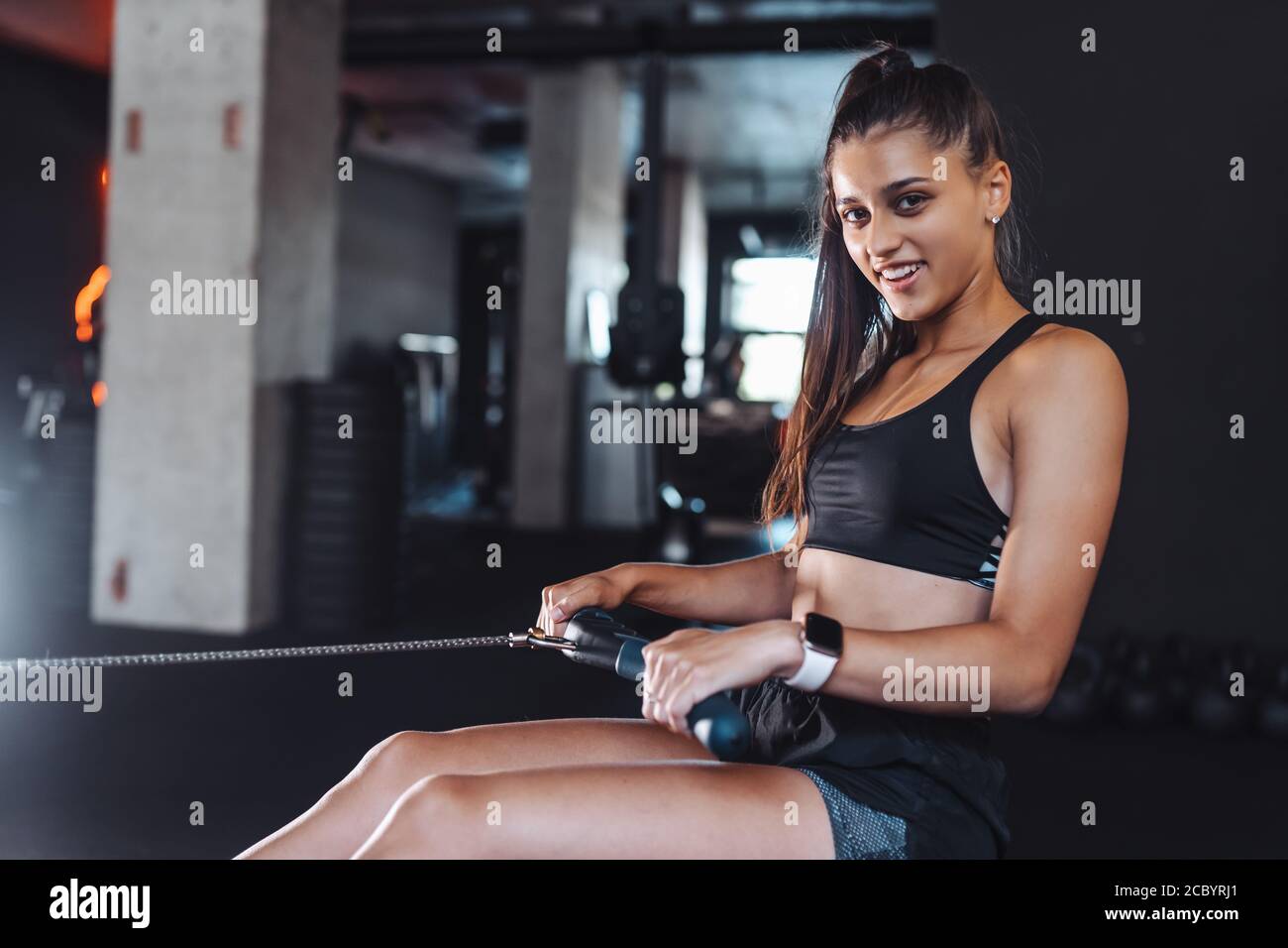Young woman training and pulling weights in seated cable row machine ...