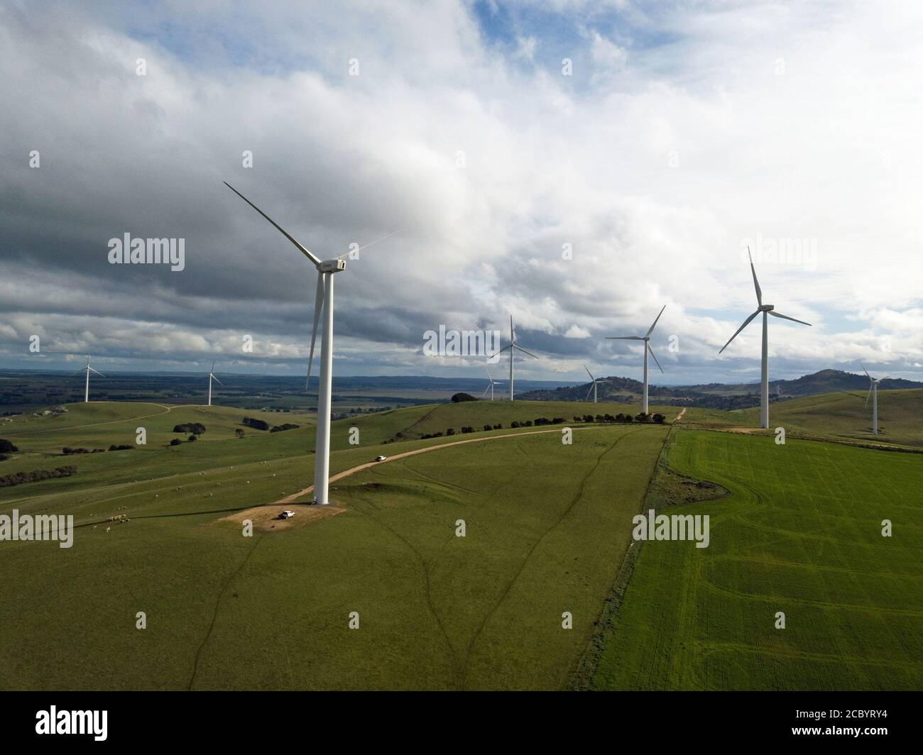 Wind farm from above in Australia with workers, green field, clouds and ...