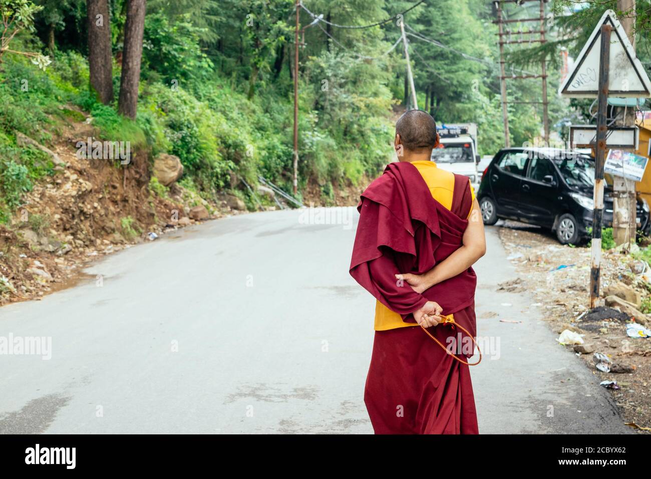 Old Indian Tibetan monk in red clothes with his back turned walking ...