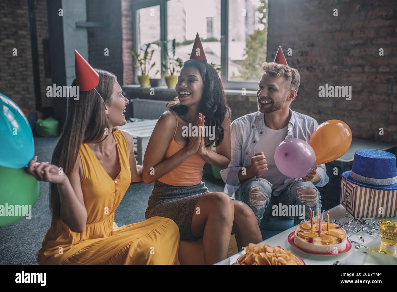 Two women and a man celebrating a birthday together Stock Photo - Alamy